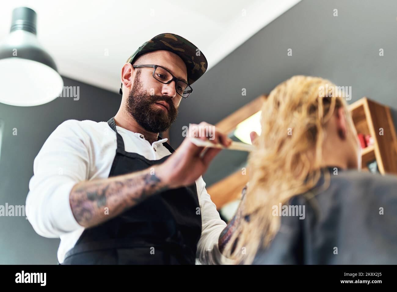 Hes the best in the business. a handsome male hairdresser styling and ...