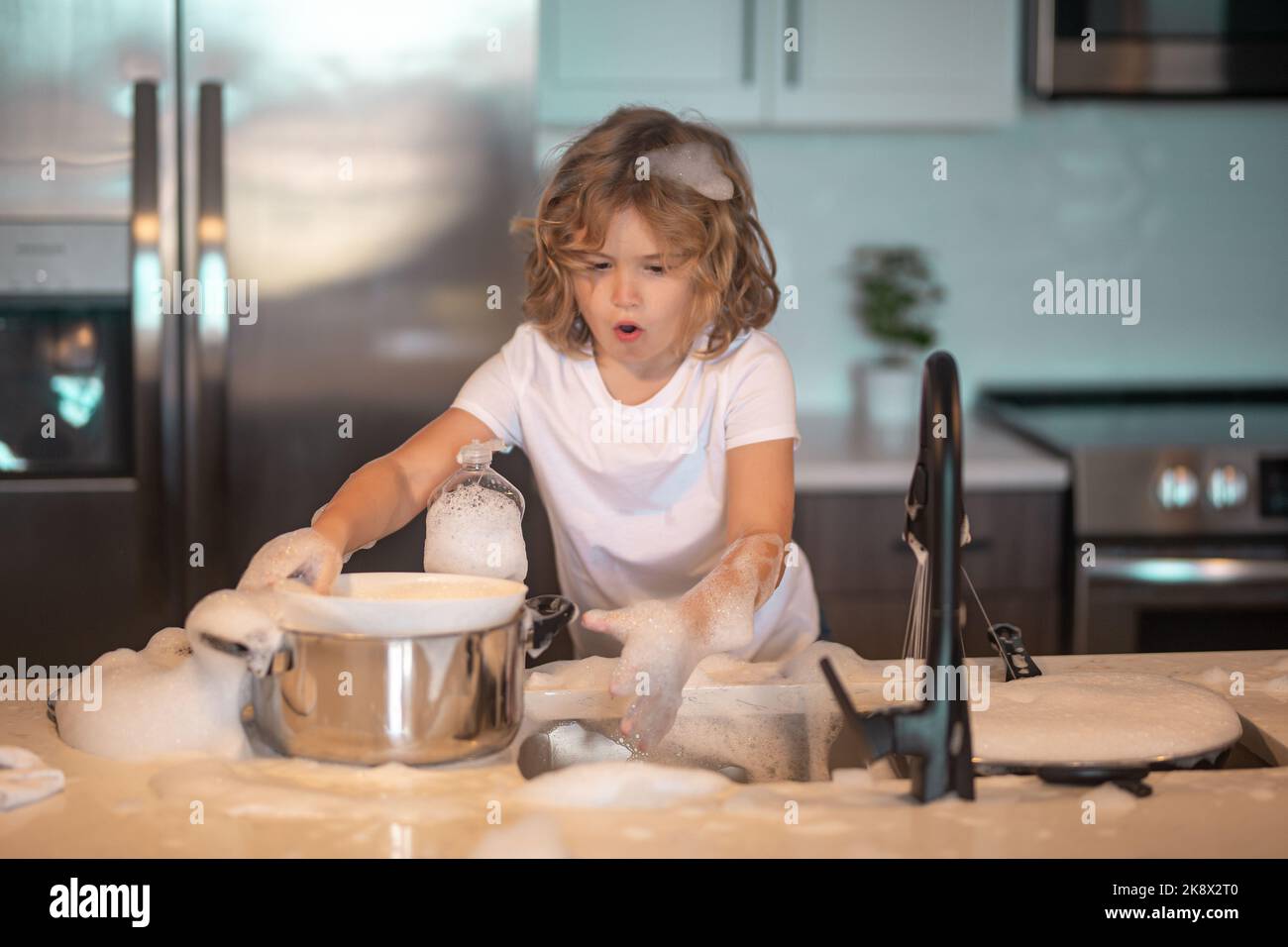 Funny twin boys helping in kitchen with washing dishes. Children having ...