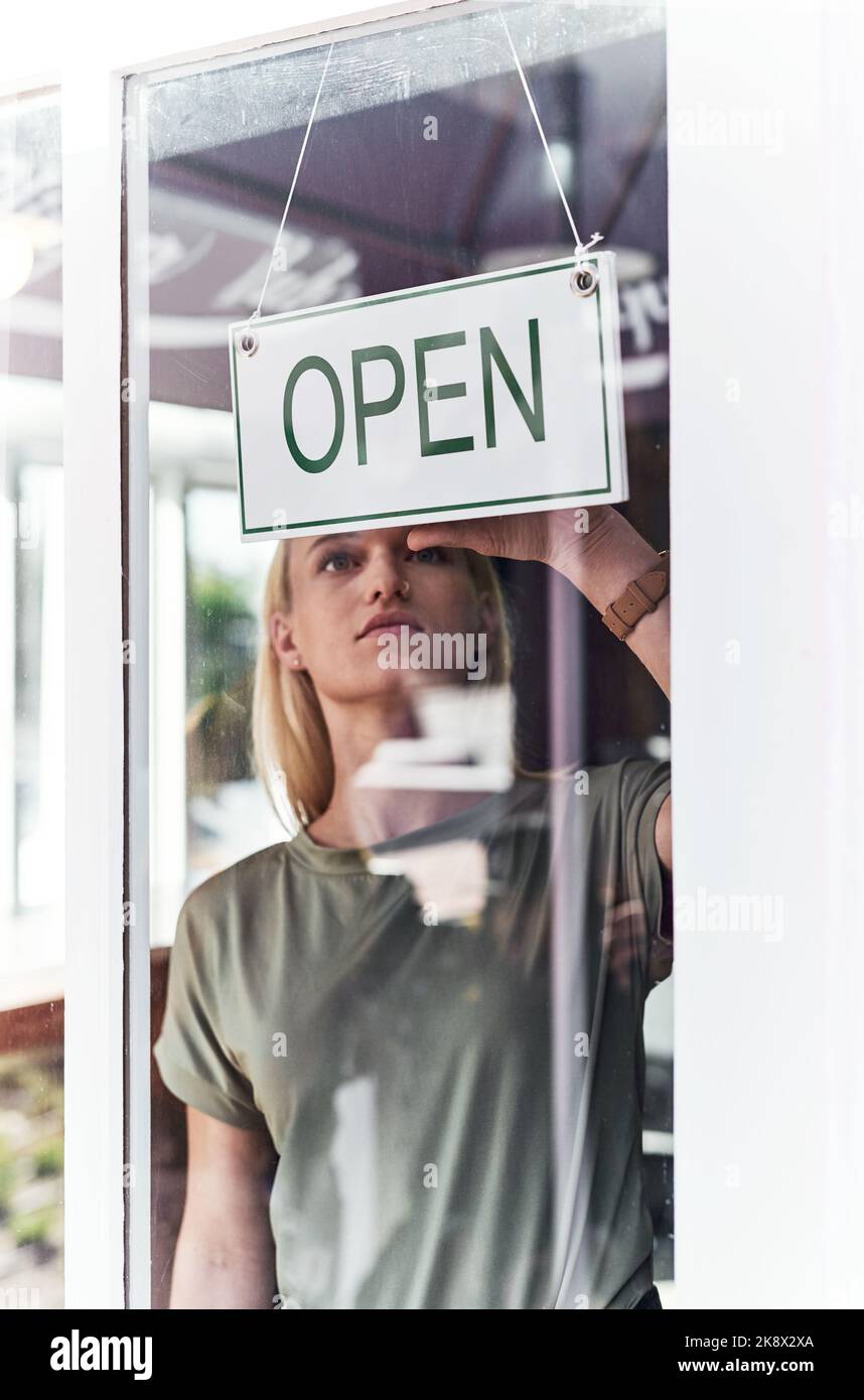 Were open for business. an attractive young hairdresser hanging up an ...