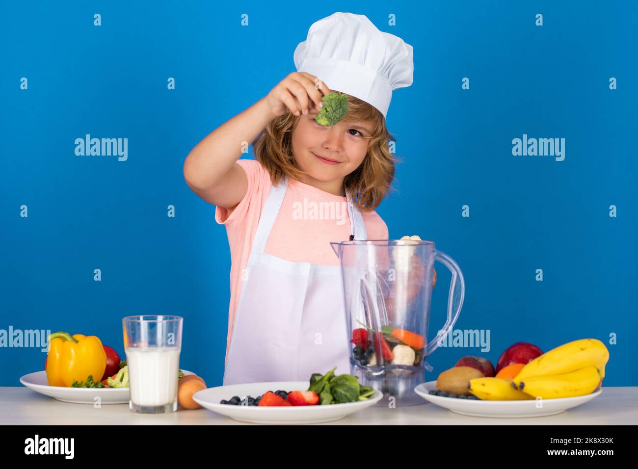 Child chef hold broccoli isolated on blue. Funny little kid chef cook ...