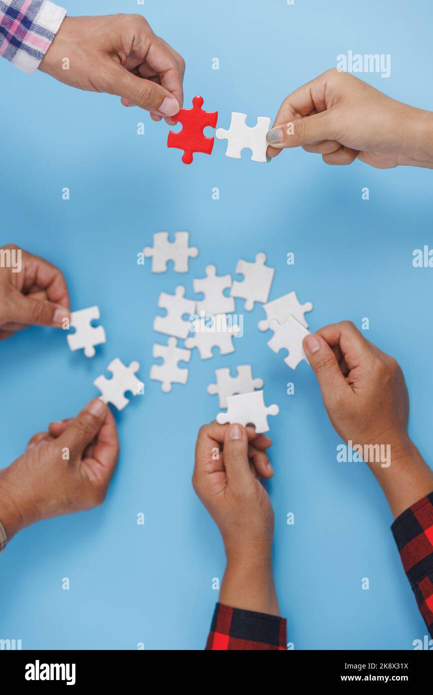 Closeup of businesspeople holding jigsaw puzzle on a blue background ...