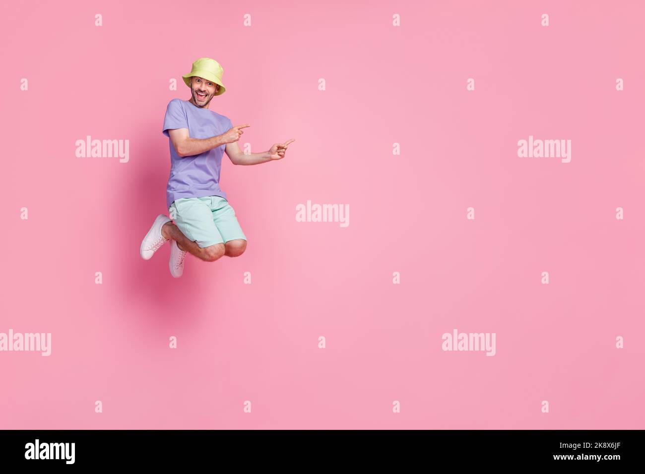 Full size photo of nice young man jumping pointing empty space enjoy ...