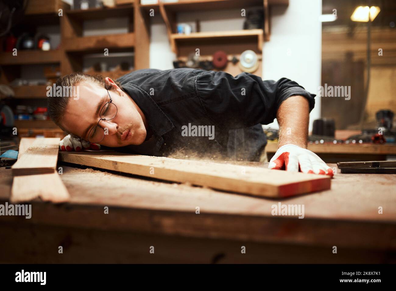 Now for the finishing touch. a focused young male carpenter blowing ...