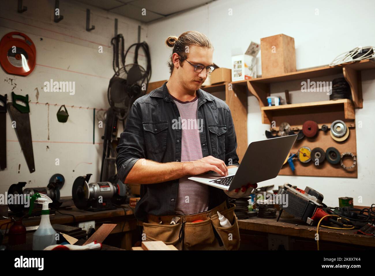 Doing some research. a focused young male carpenter working on his ...