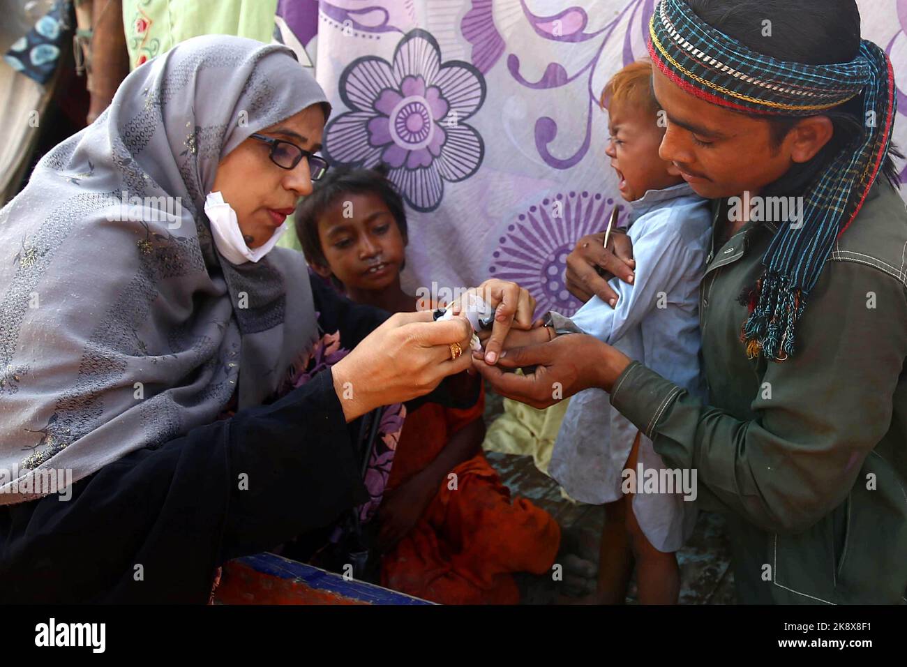 Karachi. 24th Oct, 2022. A health worker marks the finger of a child ...