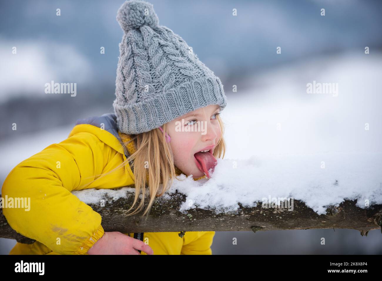 Winter girl eating snow outdoor. Funny christmas kids lick snow with ...