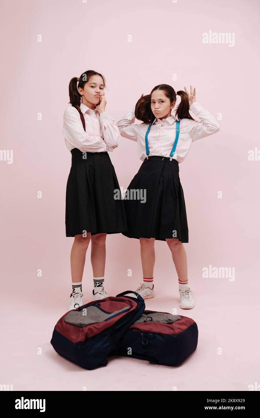 Two twin schoolgirls with twin tails puffing cheeks posing for a photo ...