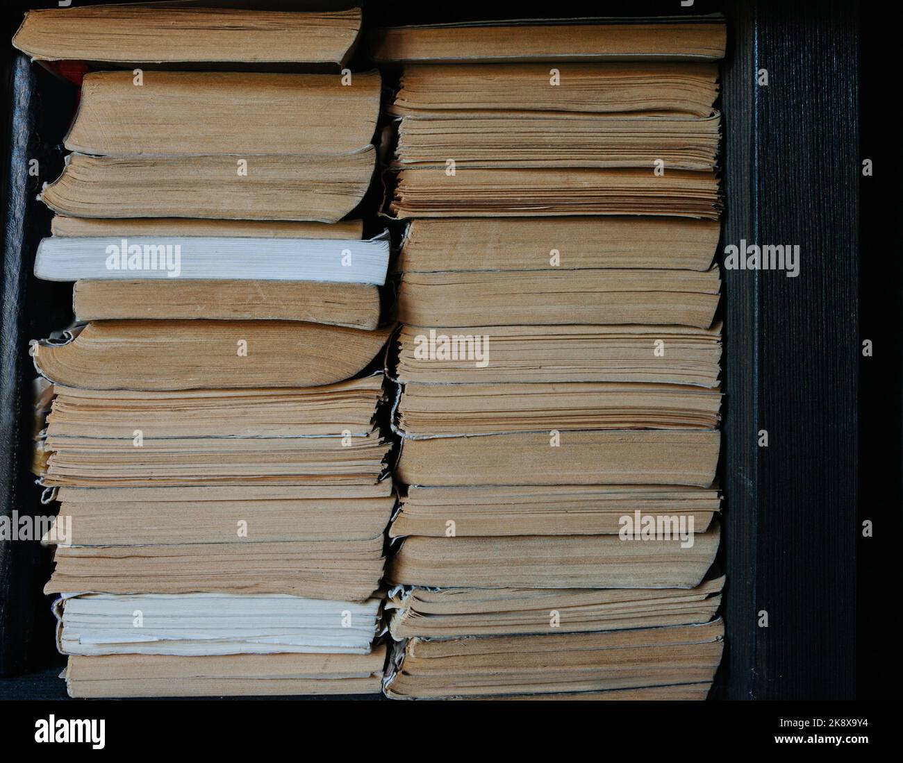 Edges of old books in two stacks in bookshelf niche. Paper yellowed ...
