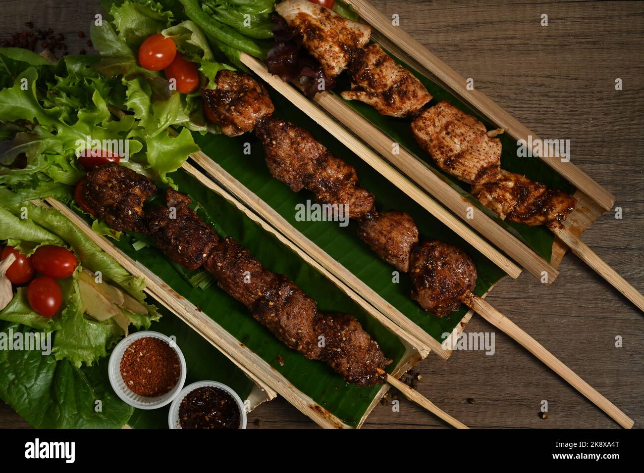 Grilled meat skewers served in bamboo barrel plate with Chinese spices and vegetable on rustic ...