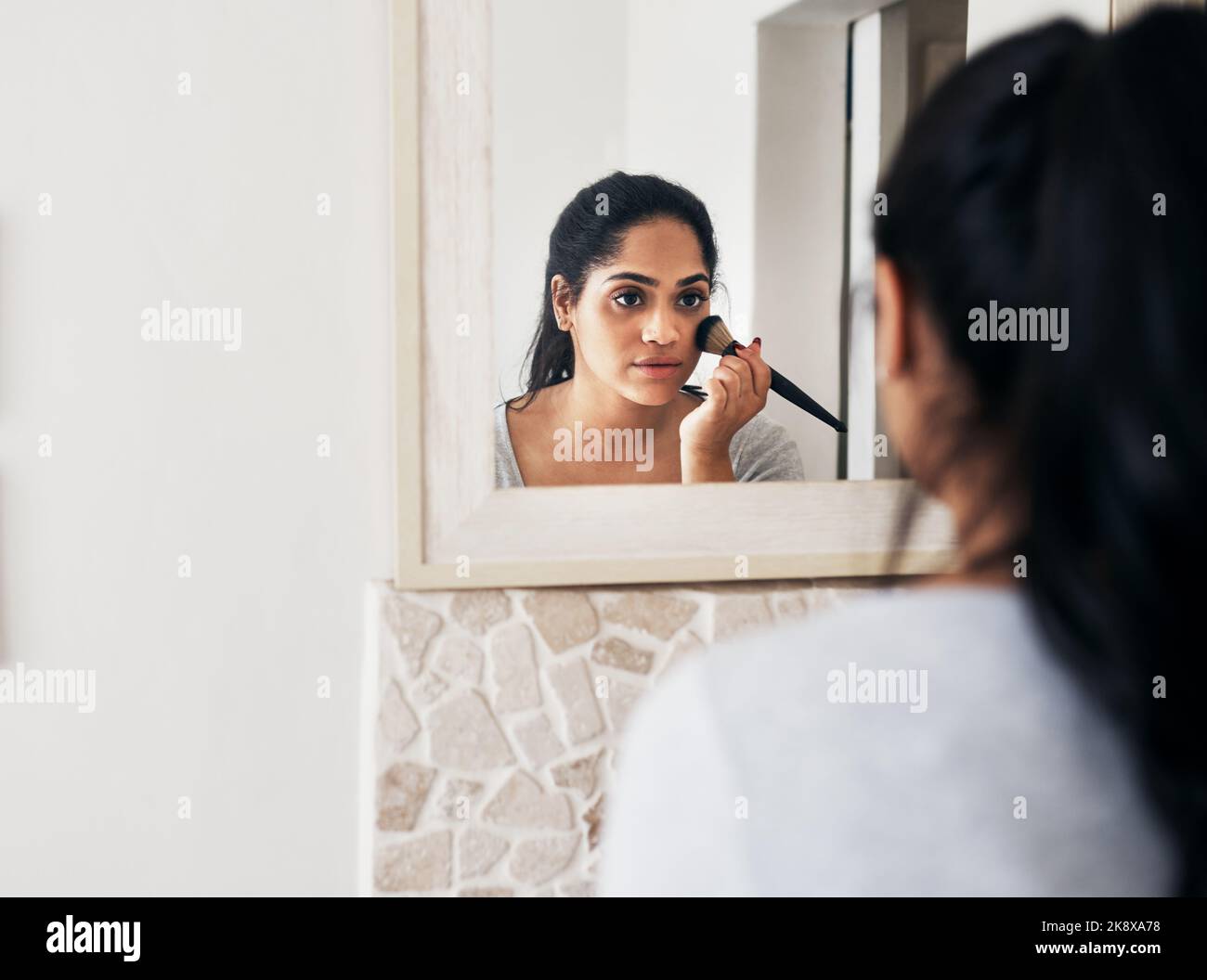 Im going for the natural look. a young woman applying makeup while ...