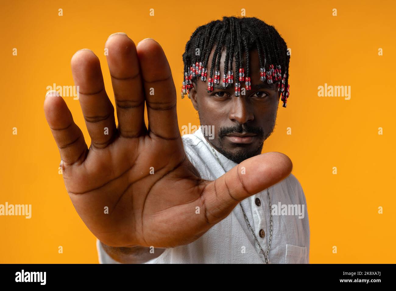 Portrait of serious African male showing hand stop sign on yellow ...