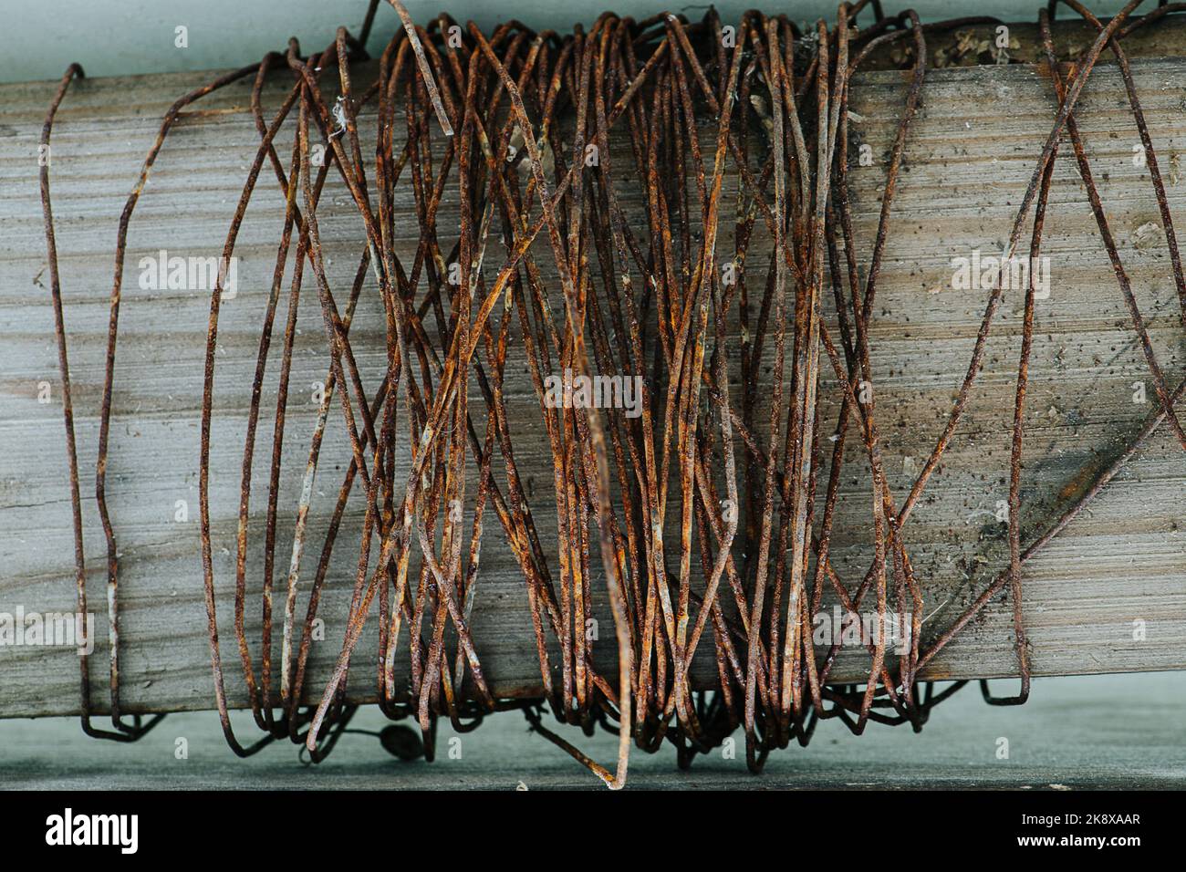 Old rusted steel wire coiled around a wooden plank. Bent in thinned ...