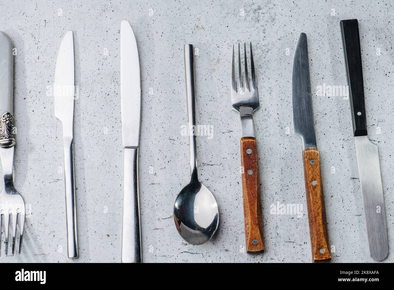 Cutlery on a table surface. Knifes, forks and spoon made of stainless ...