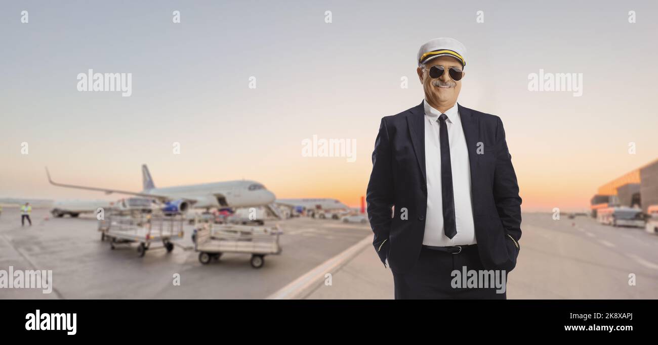 Mature pilot in a uniform posing on an airport apron Stock Photo - Alamy