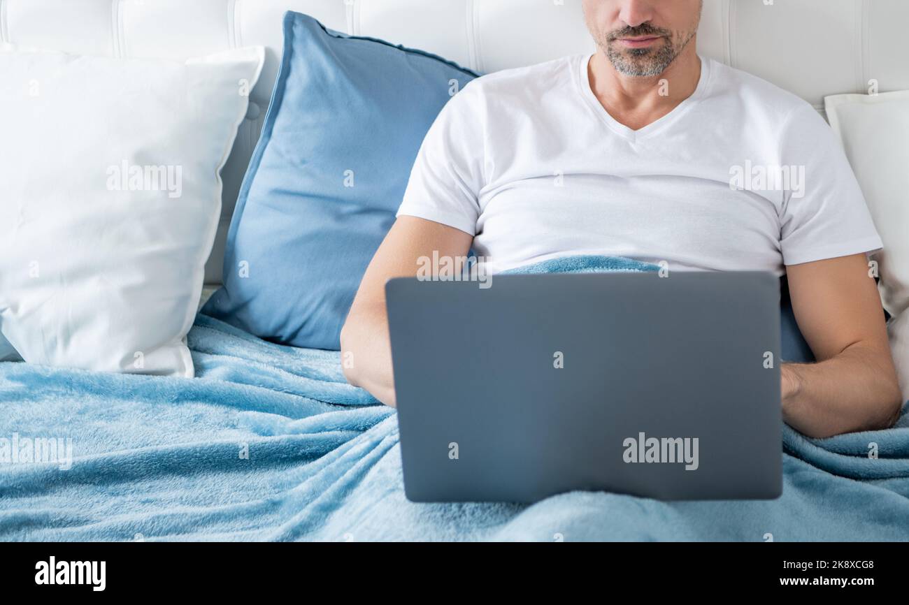 busy mature man working on laptop in bed Stock Photo - Alamy