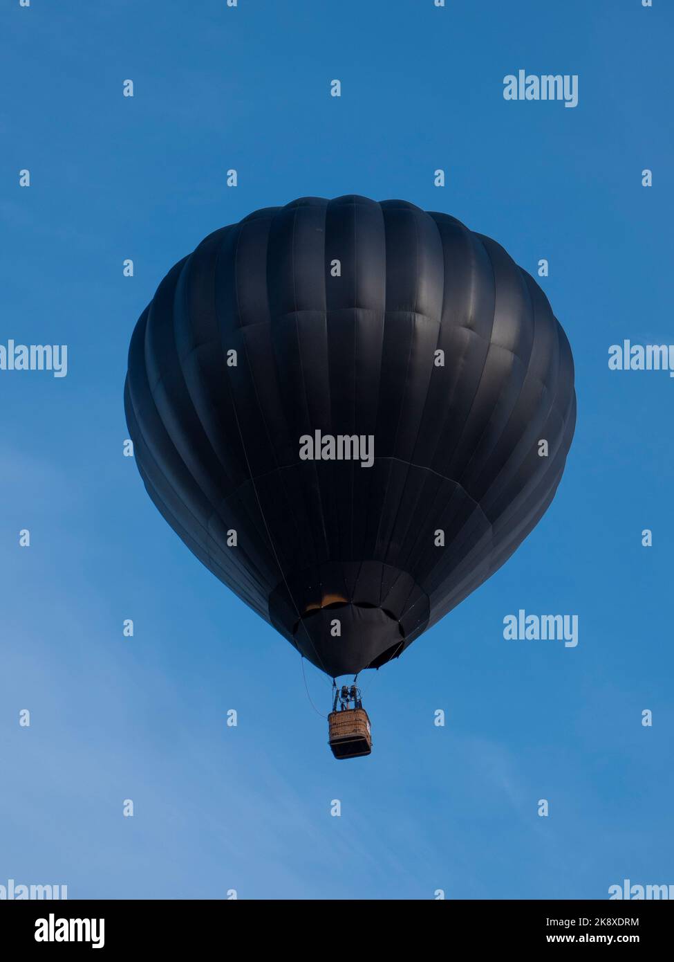 A pitch black hot air balloon high in the beautiful blue sky Stock ...