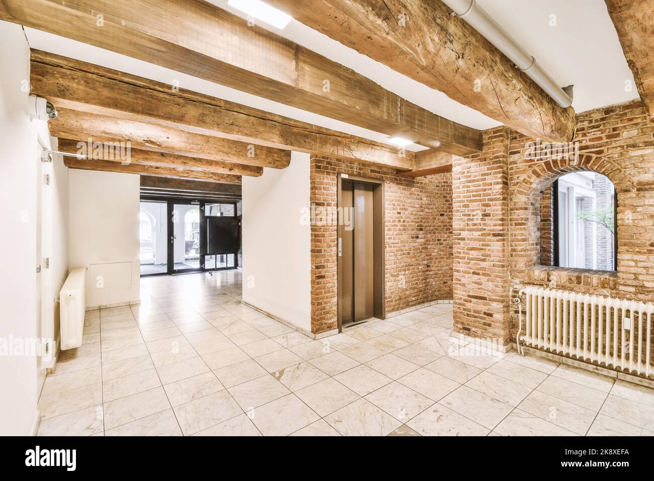 Staircase and elevator located near door and brick wall in hall of ...