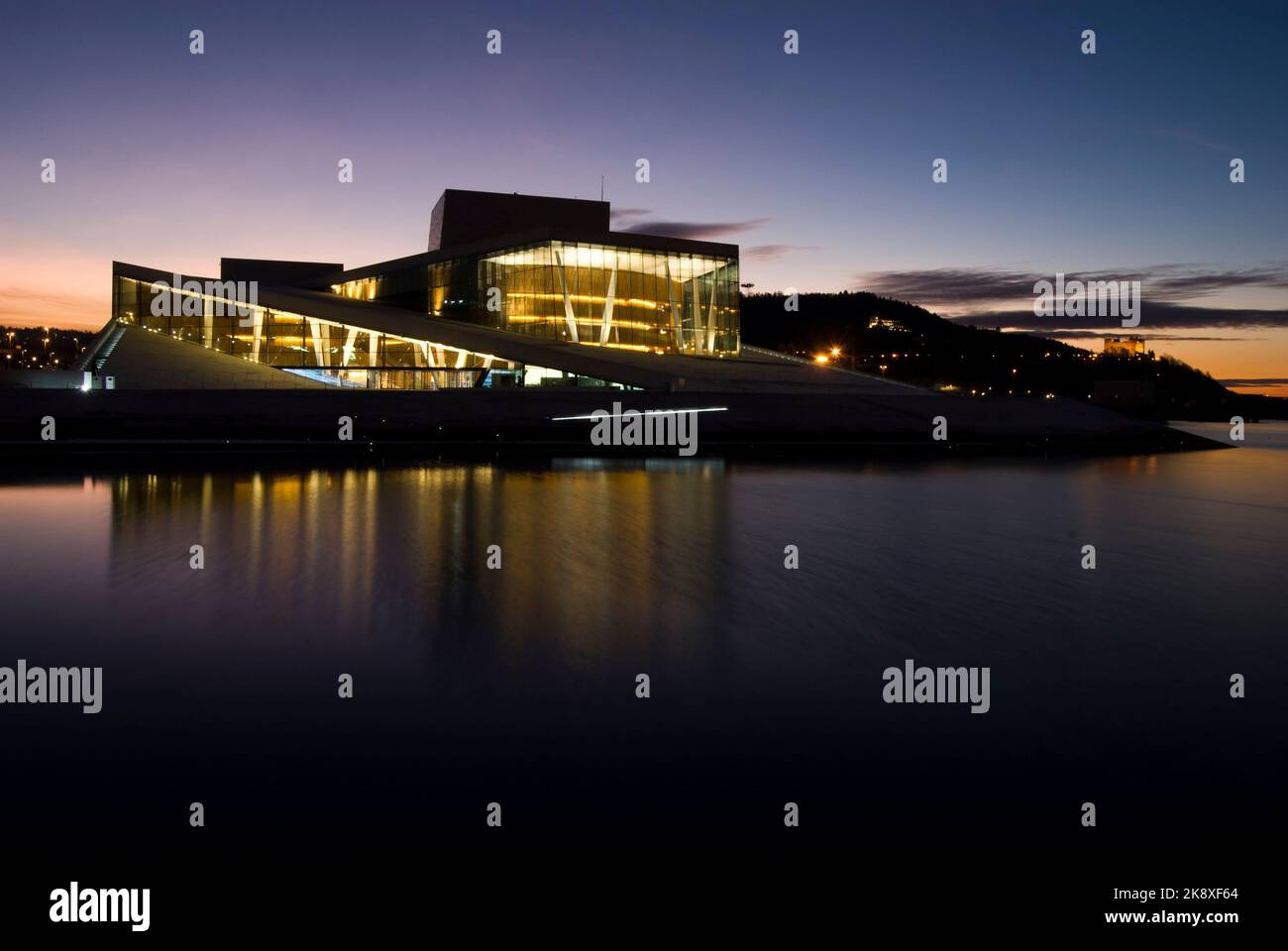 A scenic view of a calm reflective lake and Oslo opera house with ...