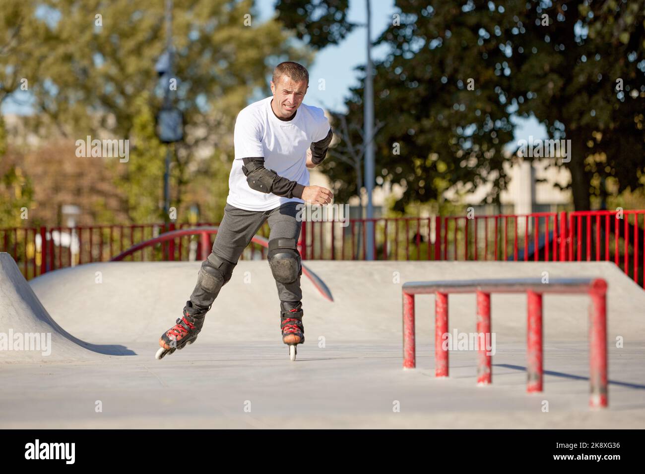 Mature male inline roller training in public skate park. Practicing ...