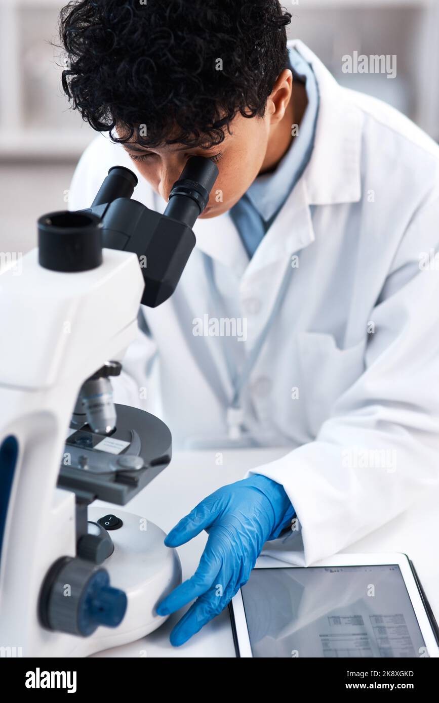 Stay curious about the world. a young scientist using a microscope in a ...