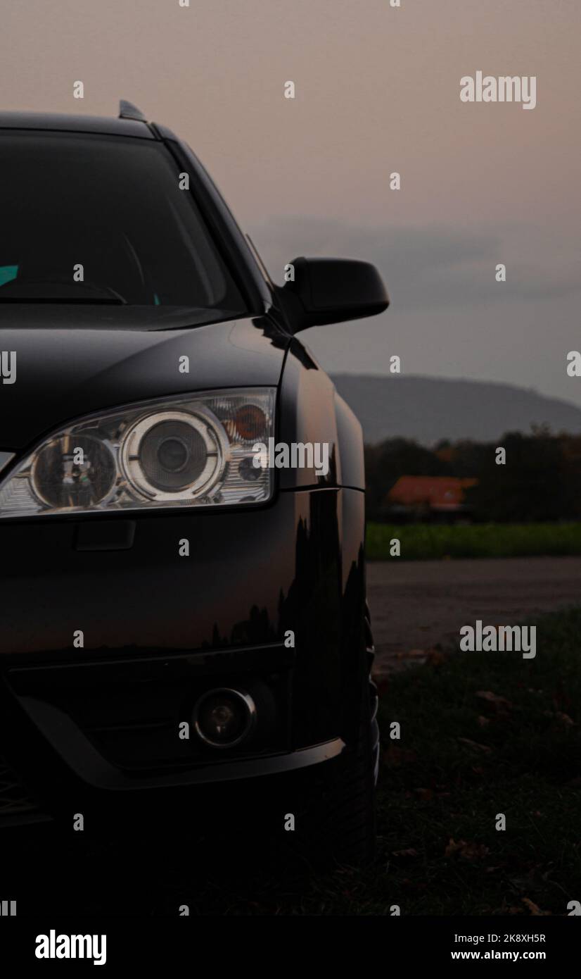 A front view shot of a shiny luxury car outdoors under sunset sky ...