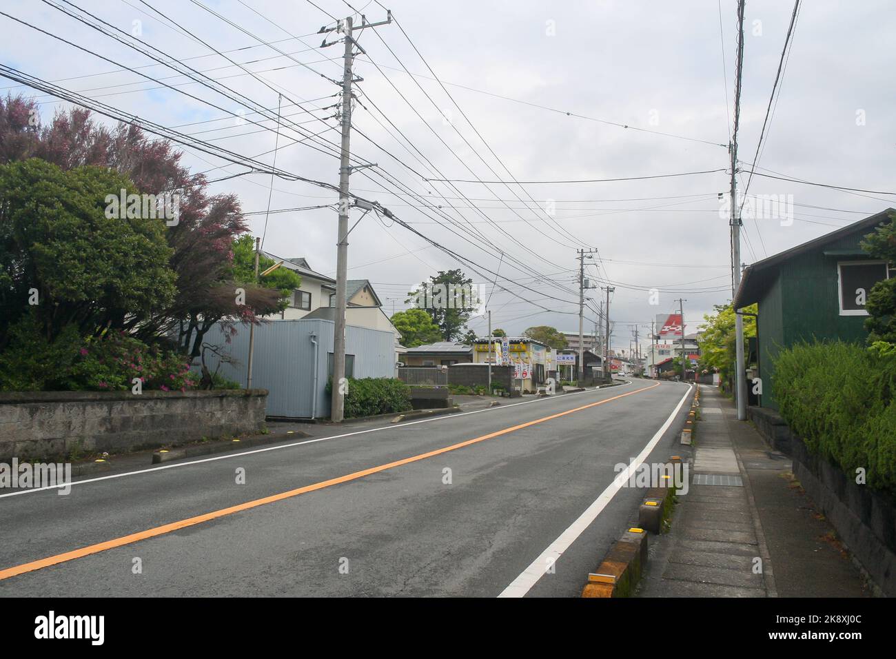 View of empty main road in small industrial city Susono with house and ...