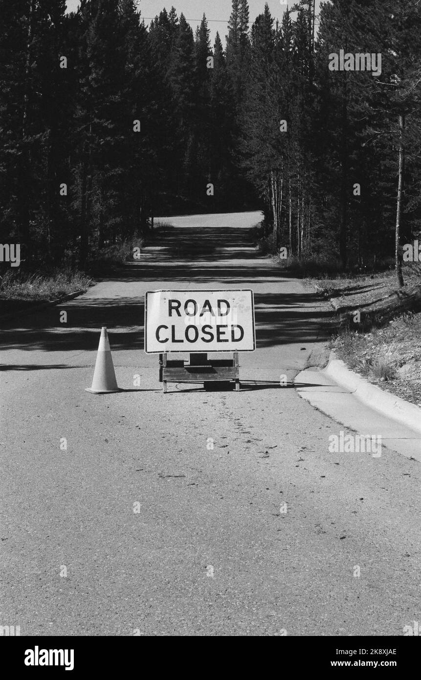 A vertical grayscale shot of a road closed sign on the road Stock Photo ...