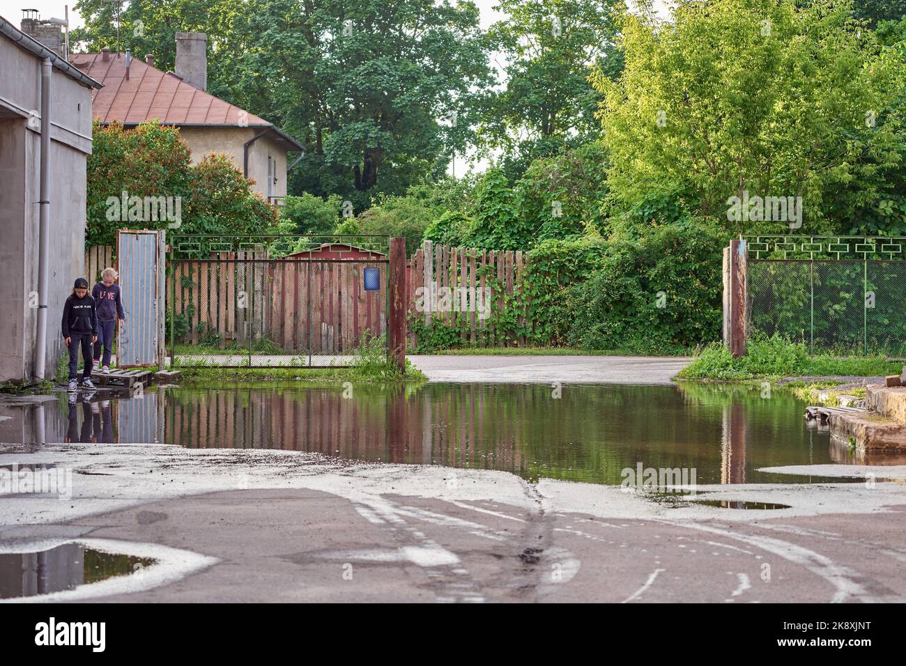 The two children trying to cross a huge puddle in the yard Stock Photo ...