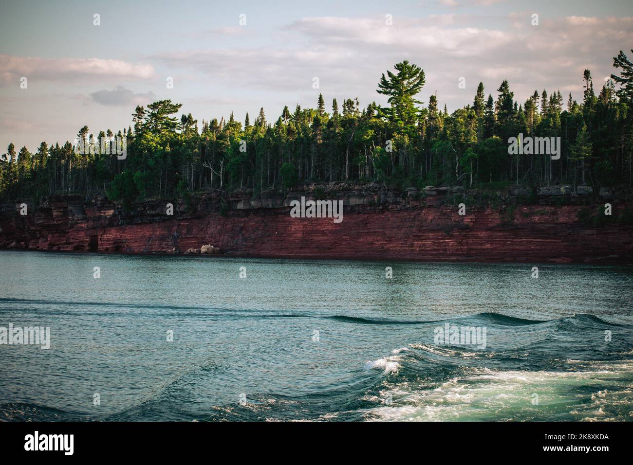 The wave crashing into the beach with cut ground layers under fir ...