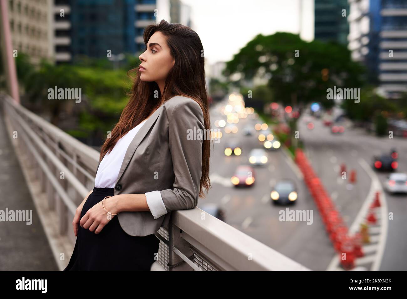 Laid back vibes. an attractive young woman leaning against a balcony in ...