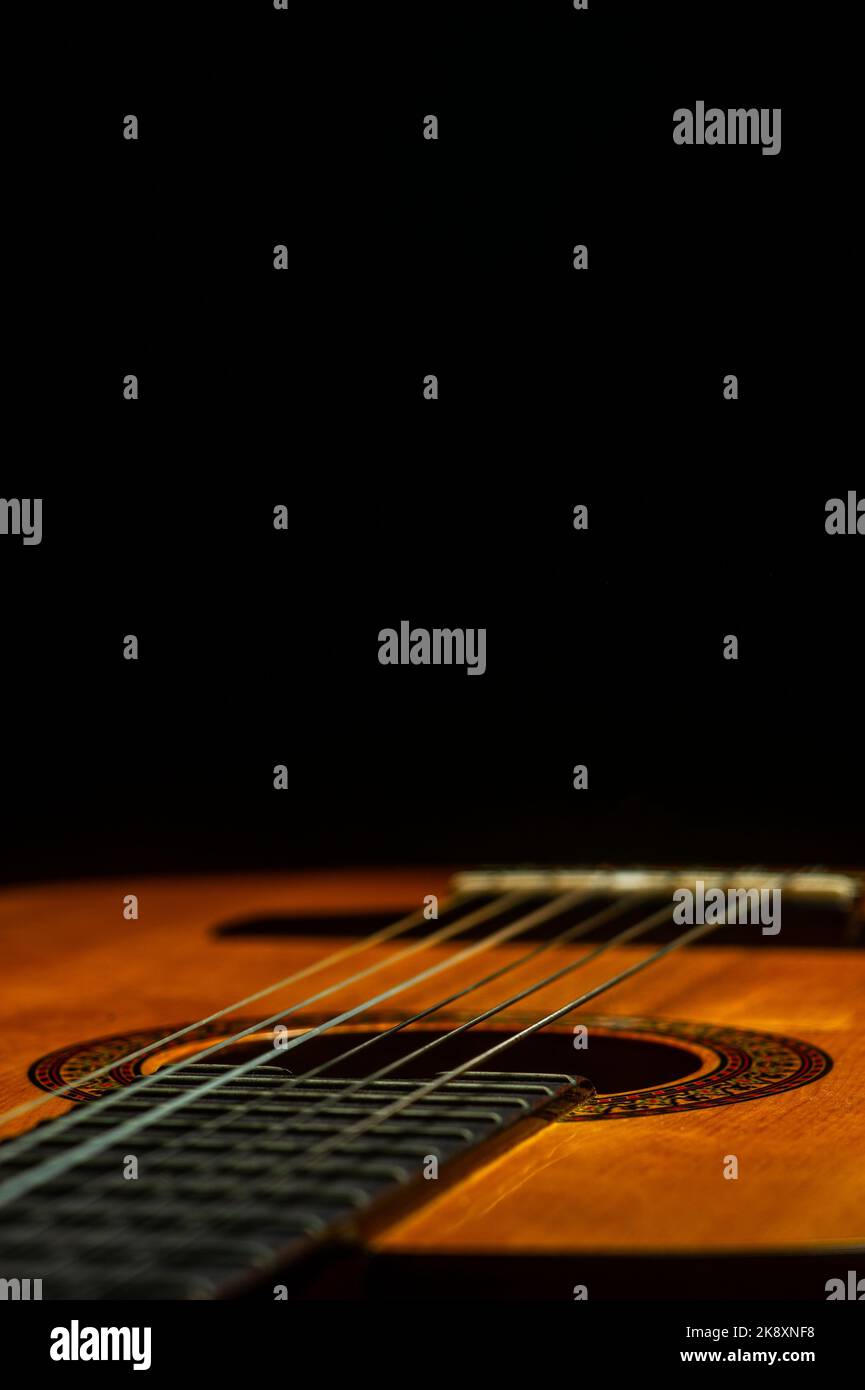 The neck of the acoustic guitar laying horizontally on isolated black ...