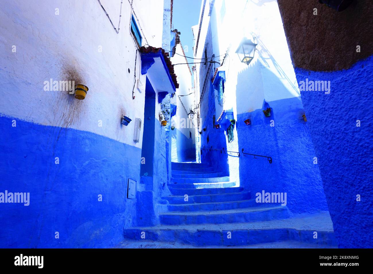 A narrow alley with a staircase in Chefchaouen city in vibrant blue and ...