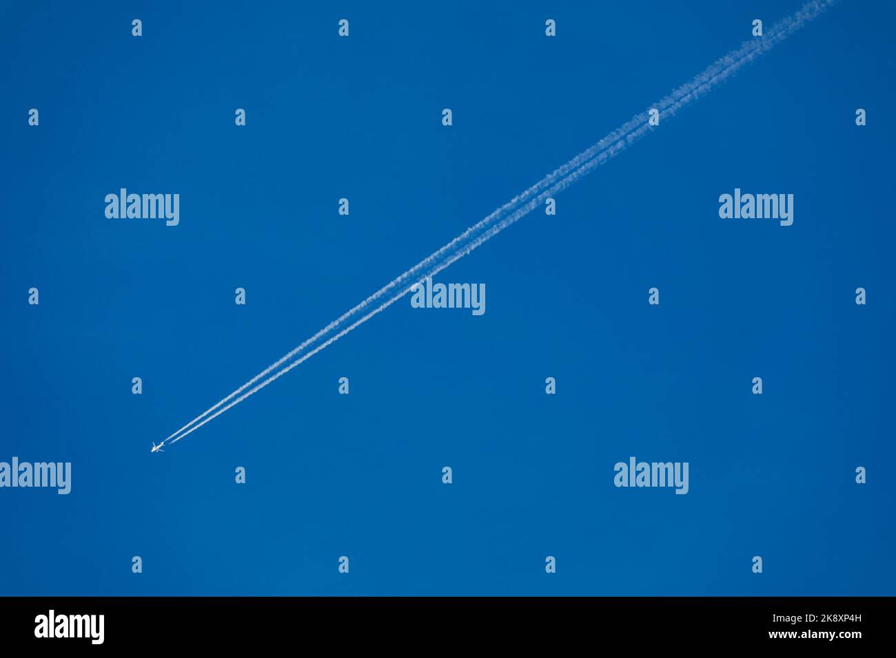 A low-angle view of an airplane flying in the sky leaving a white smoke ...