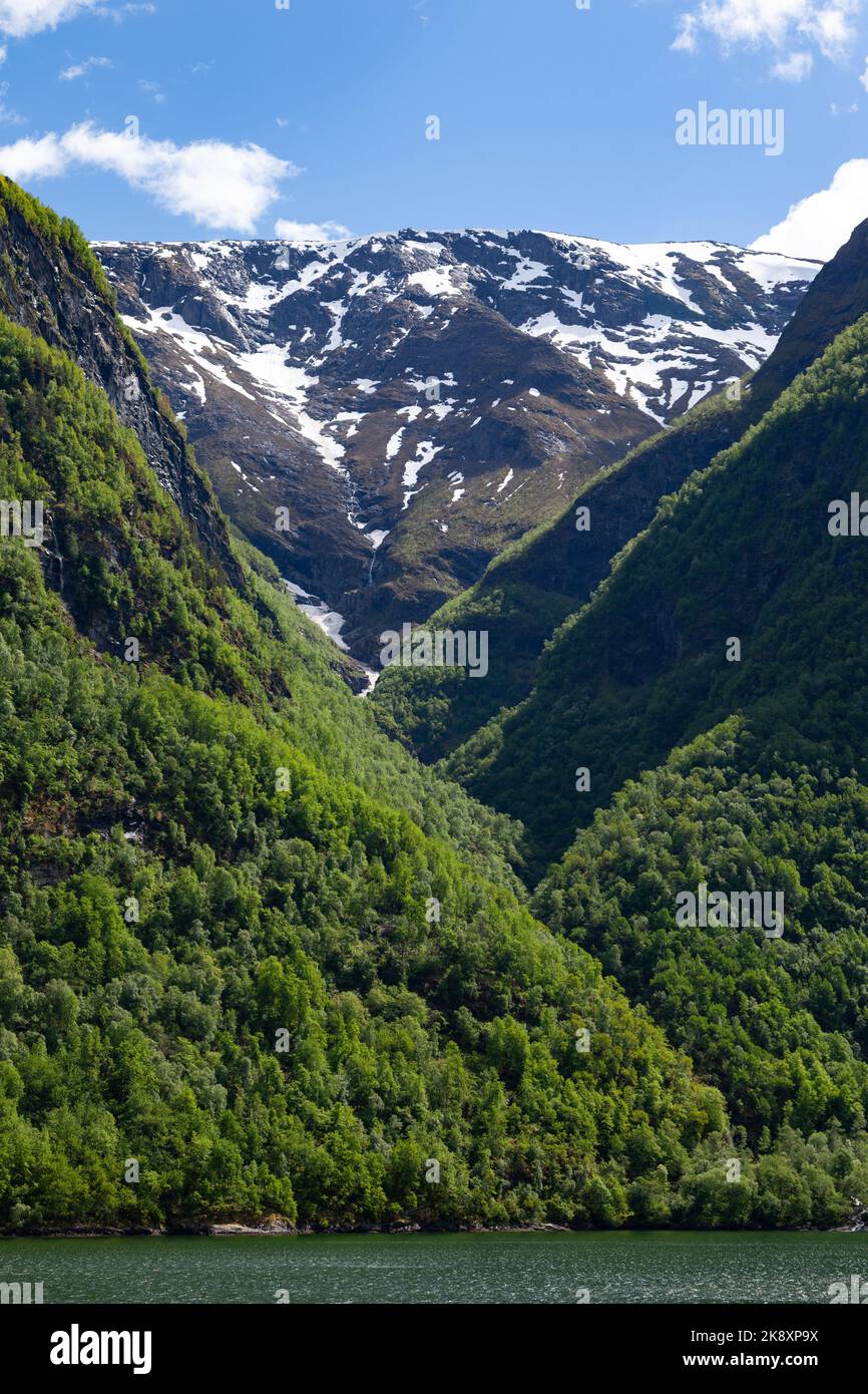 A vertical shot of Narrow Fjord surrounded by mountains covered with ...