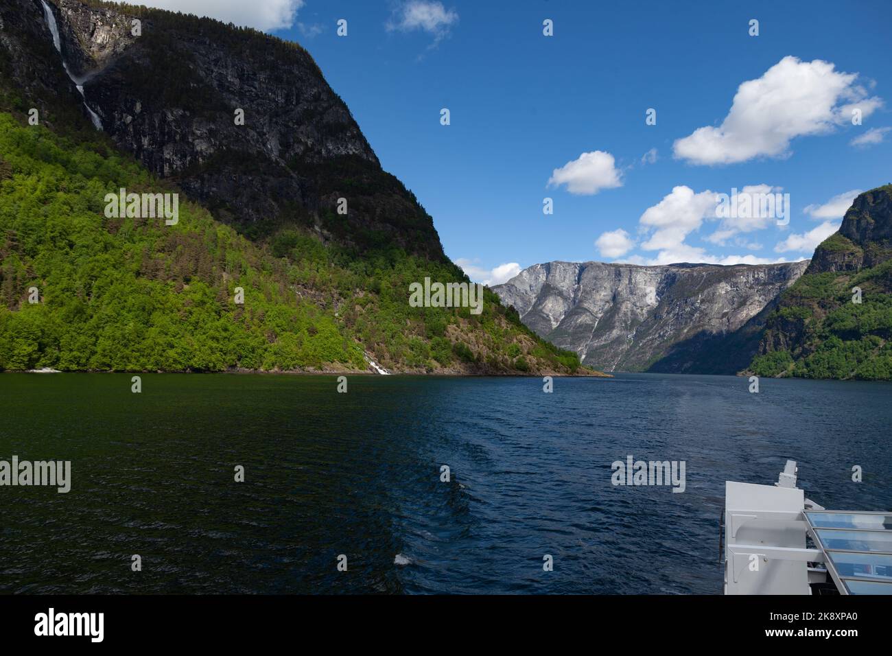 A Narrow Fjord surrounded by mountains with a waterfall in Vestland ...