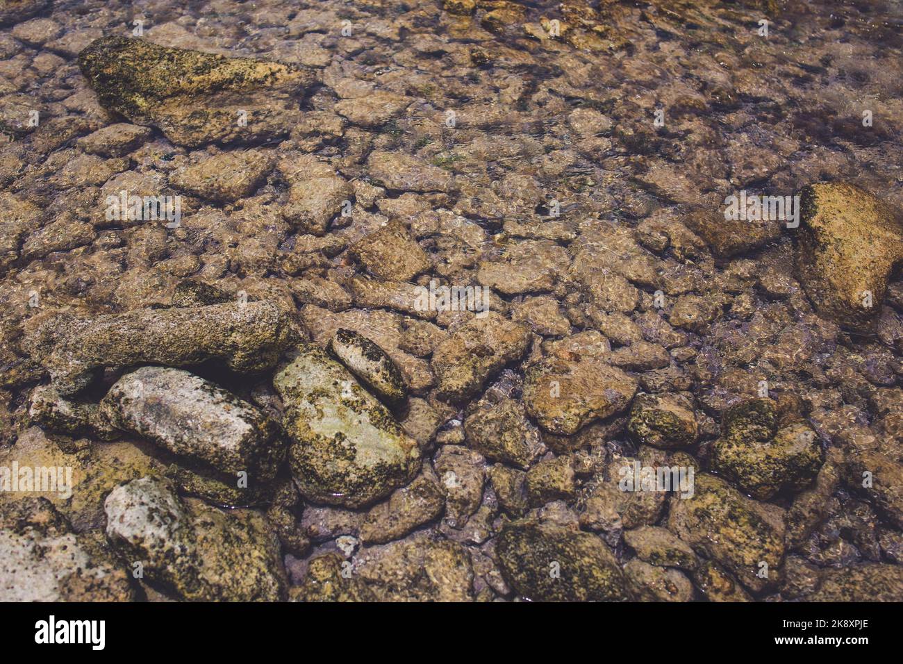 A top view shot of a clear lake filled with stones on a sunny day Stock ...