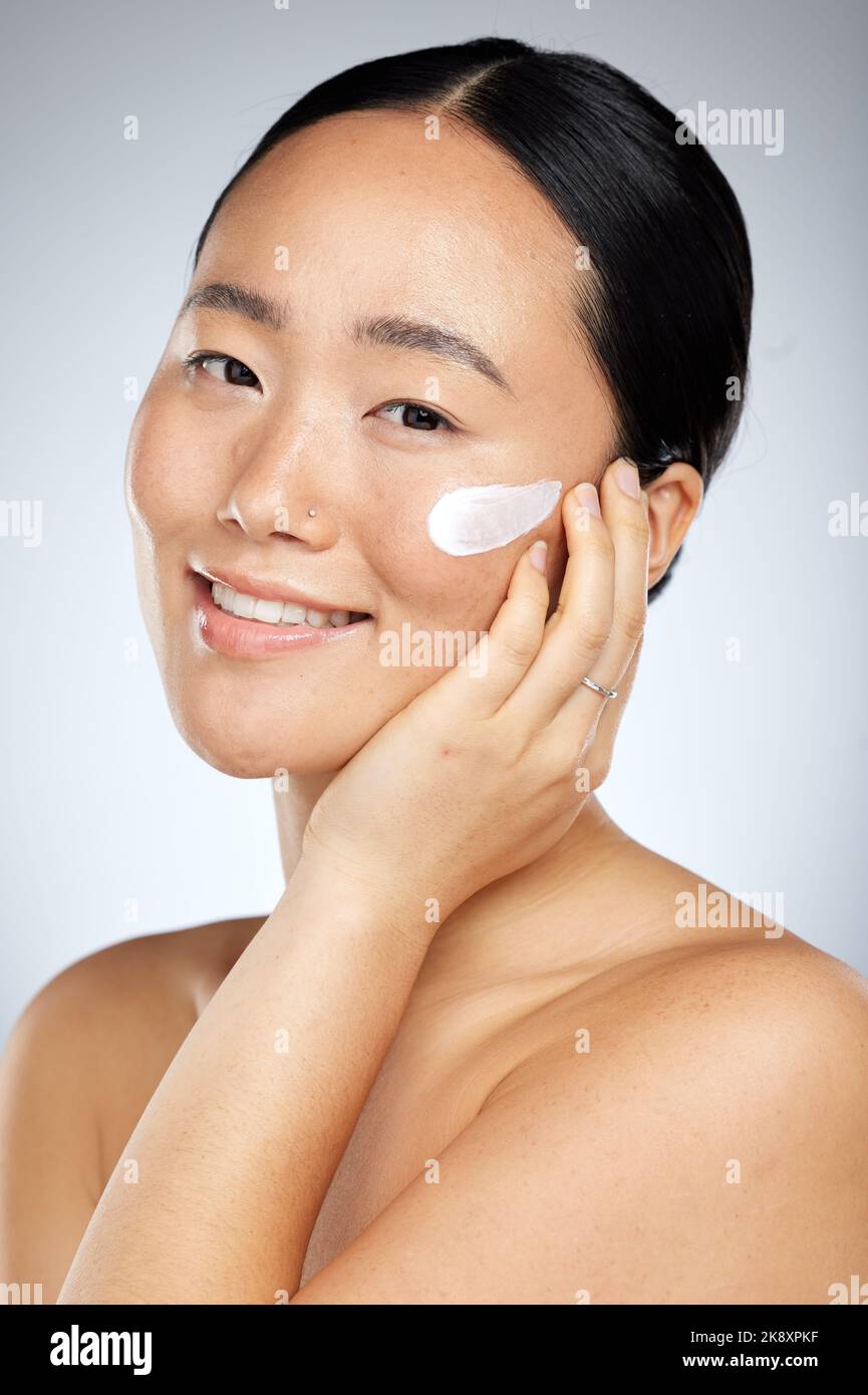 Face, beauty and skincare with an model asian woman in studio on a gray ...