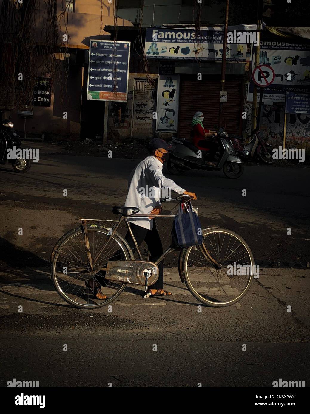 A vertical shot of a male walking while holding his bicycle in a poor ...