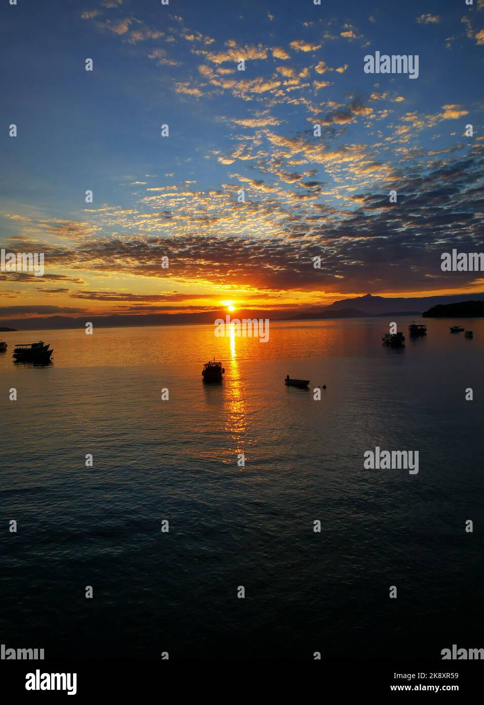 A vertical shot of vibrant sunset scene over calm sea Stock Photo - Alamy