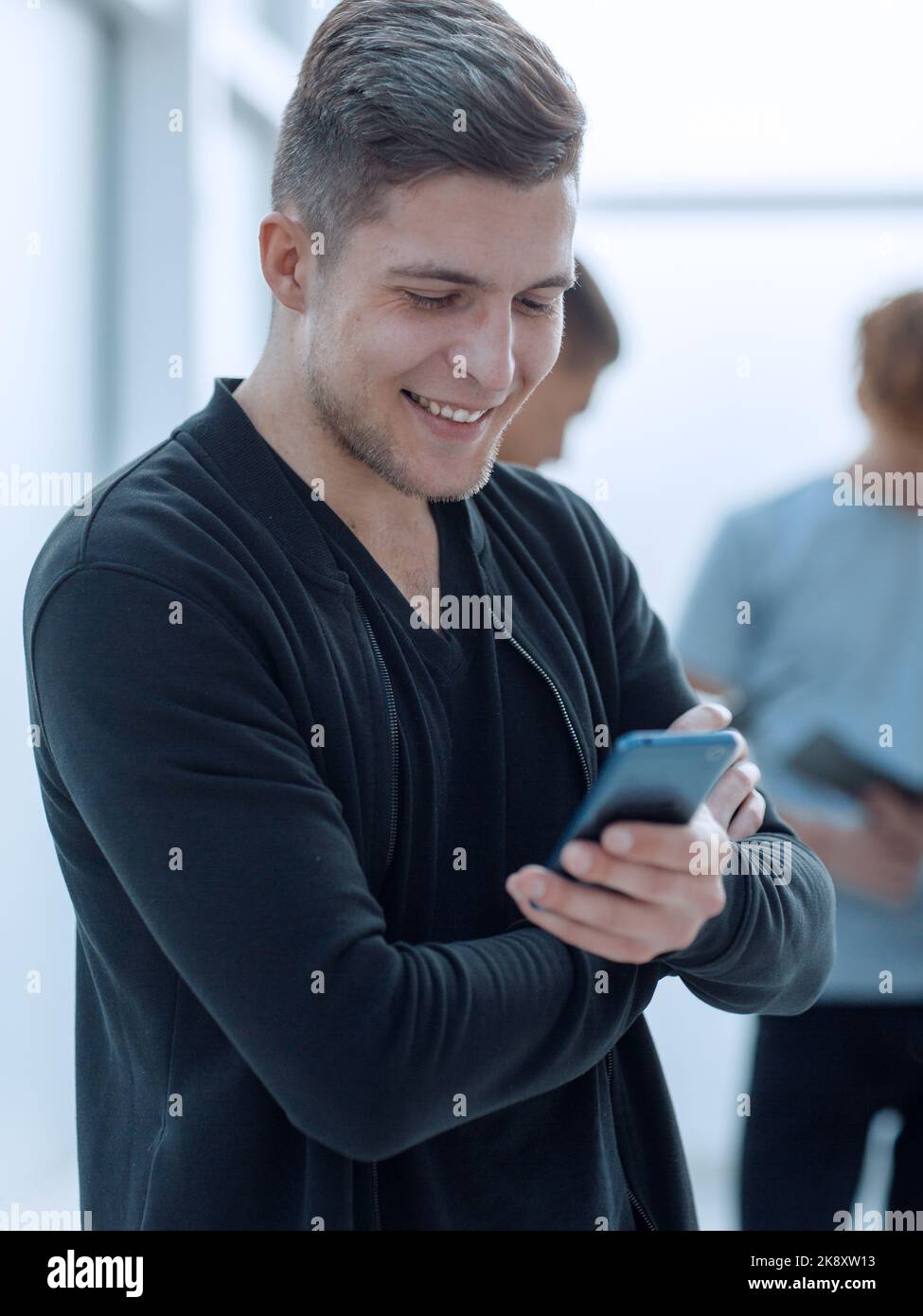 smiling young man reading a message on his smartphone Stock Photo - Alamy
