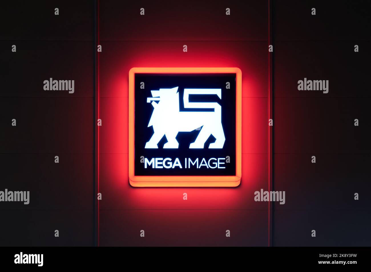 Illuminated Mega Image logo sign at night. Mega Image is a supermarket ...