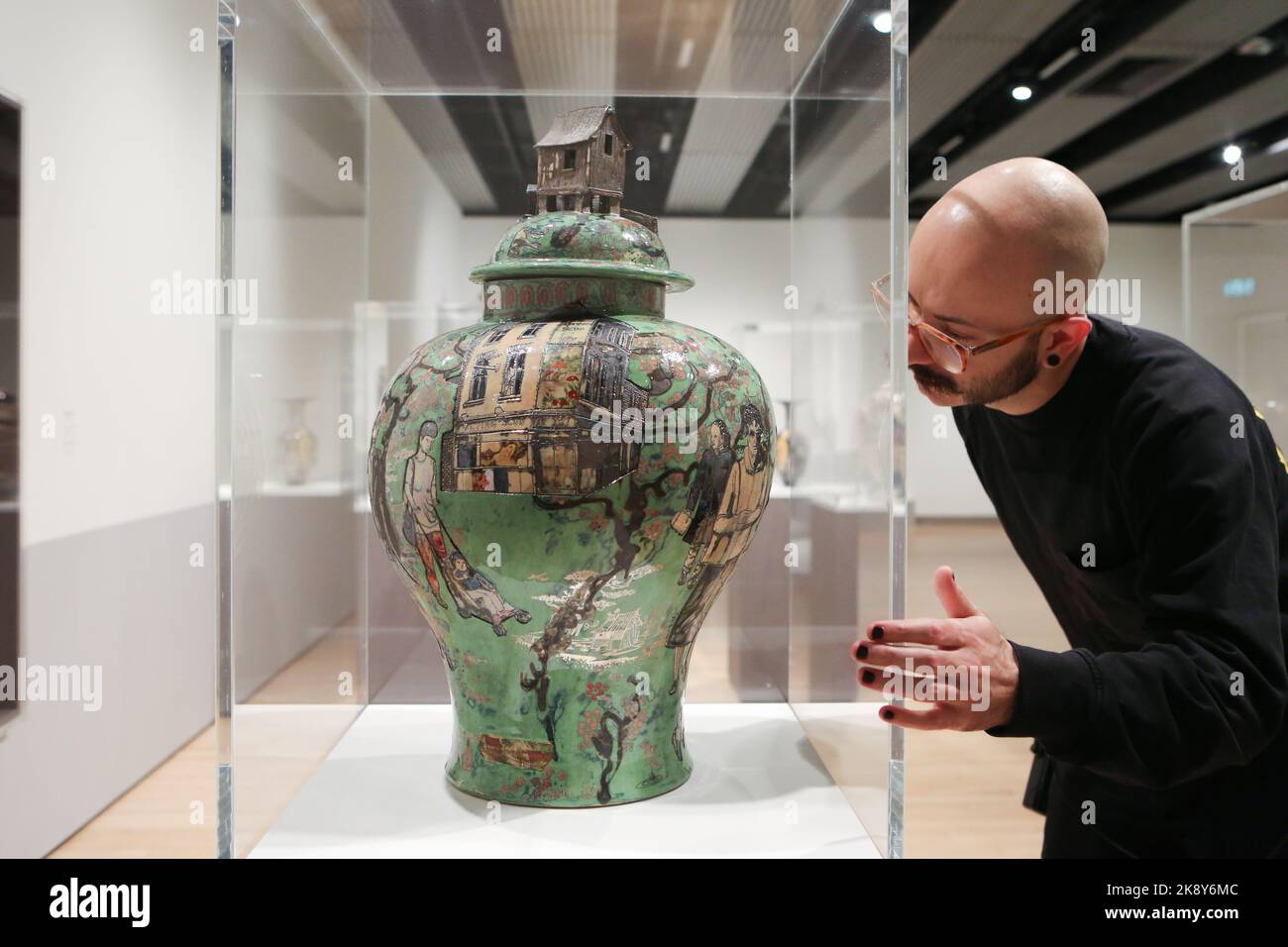 London, UK, 25/10/2022, A man takes a closer look at a glazed ceramic ...