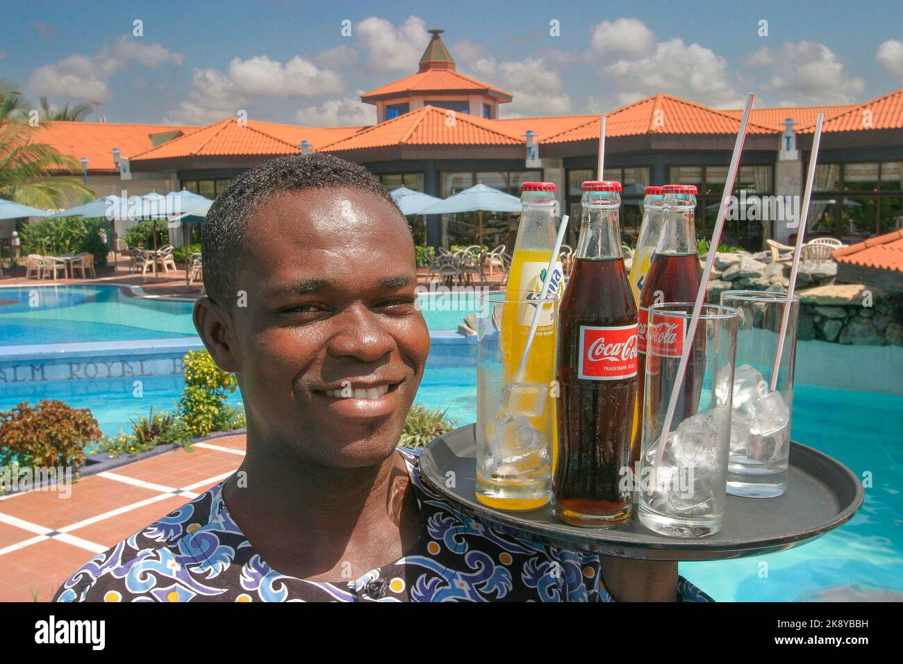 Ghana, Accra. Waiter of Hotel La Palme brings softdrinks to guests at ...