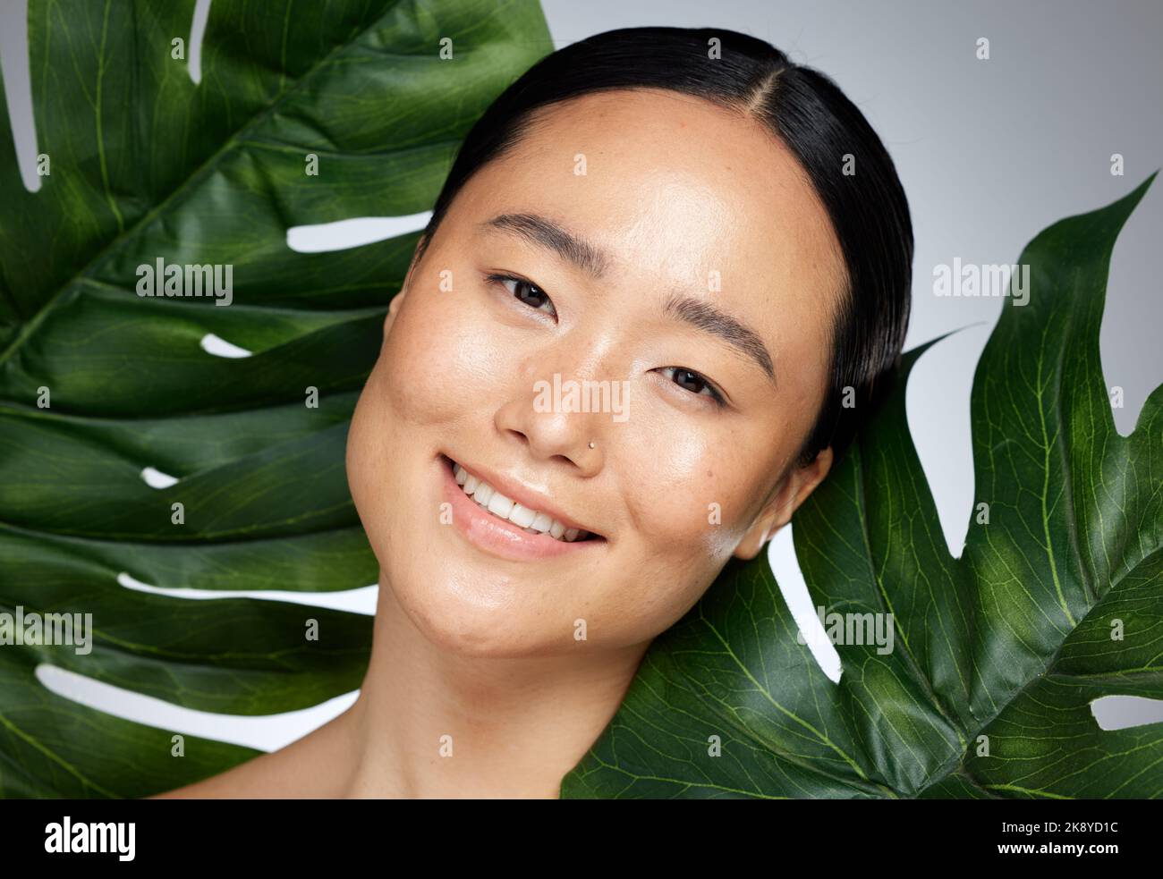 Face, beauty and asian woman with monstera leaf on gray studio ...