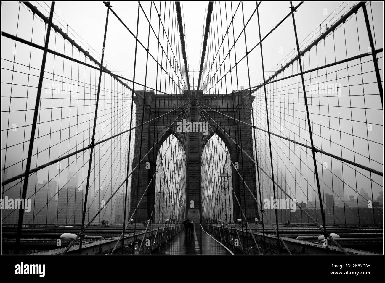The Brooklyn Bridge and its arch with traffic and ropes supporting the ...
