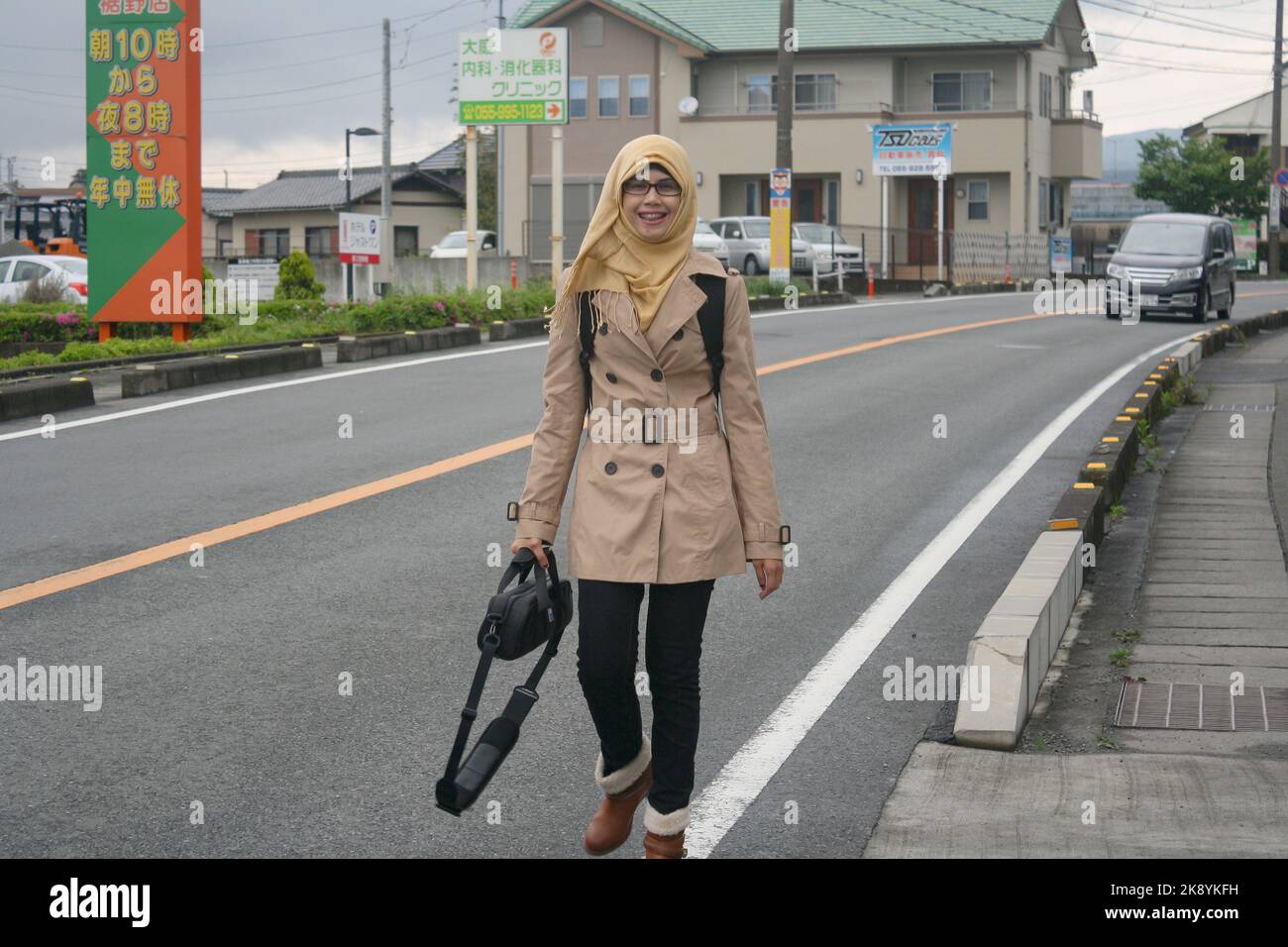 Portrait of young muslim woman wearing hijab smiling and walking on ...