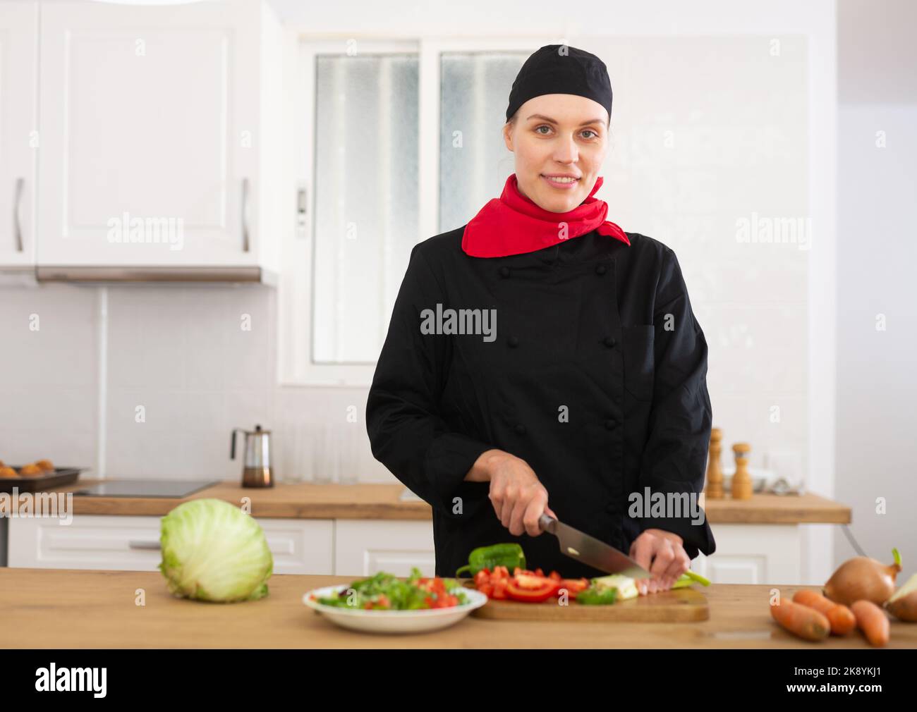 Female cook in black uniform chopping vegetables in kitchen Stock Photo ...