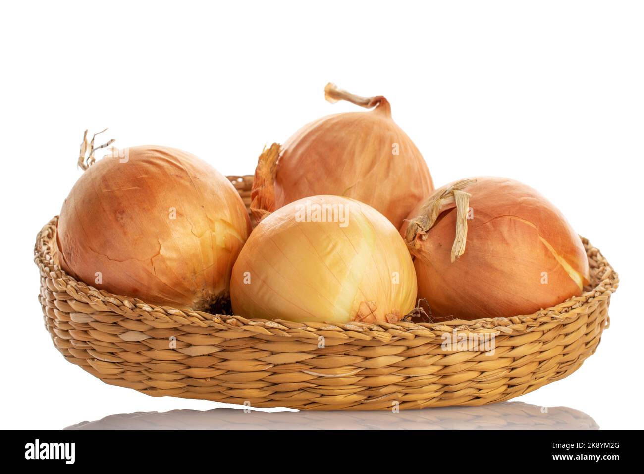 Four round aromatic onions in a straw plate, close-up, isolated on ...