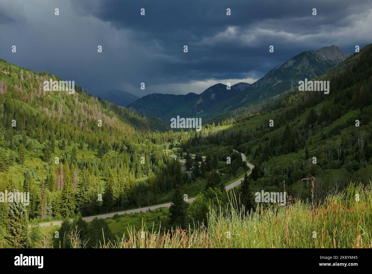 The view of a road passing through green mountains valley on a rainy ...