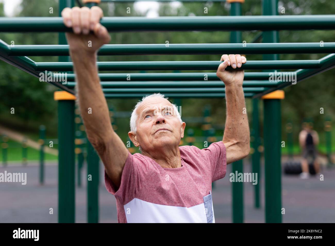 Active grandfather moves with the help of his hands on a horizontal ...